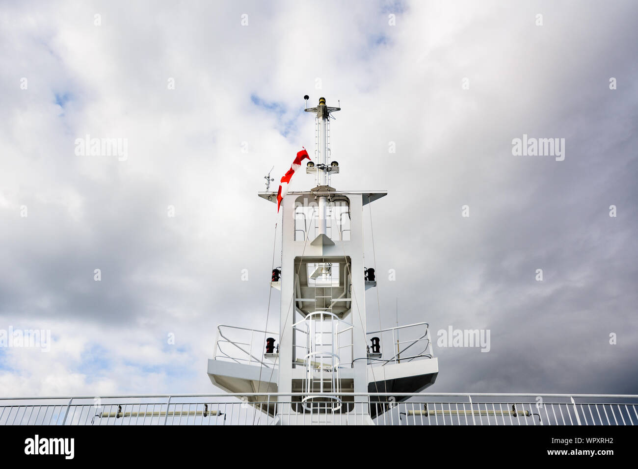 White ship's navigation tower mast with Canadian flag and cloudy sky ...