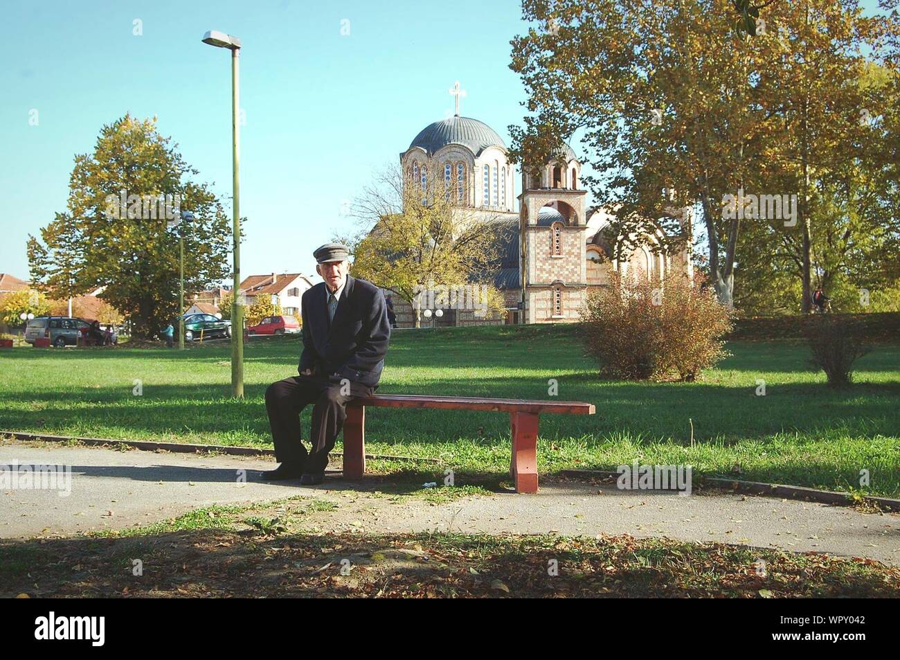 Full Length Of Man Sitting Against Historic Building On Bench At Park ...