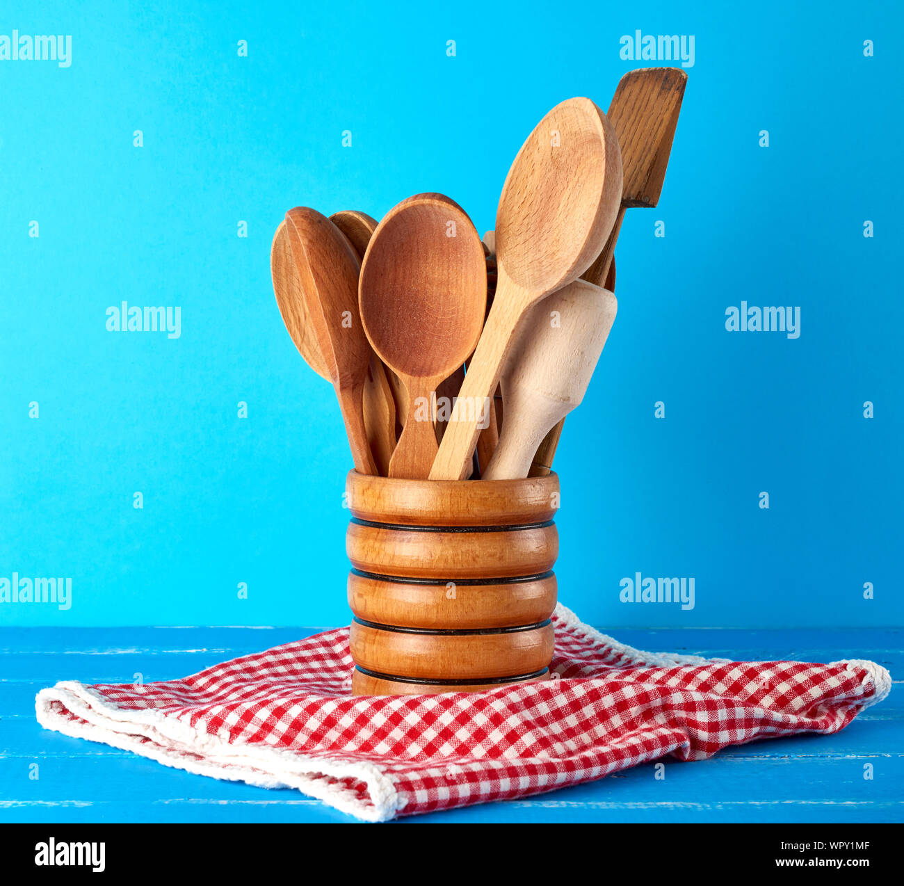 wooden spoons in a wooden container on a blue table, kitchen backdrop ...