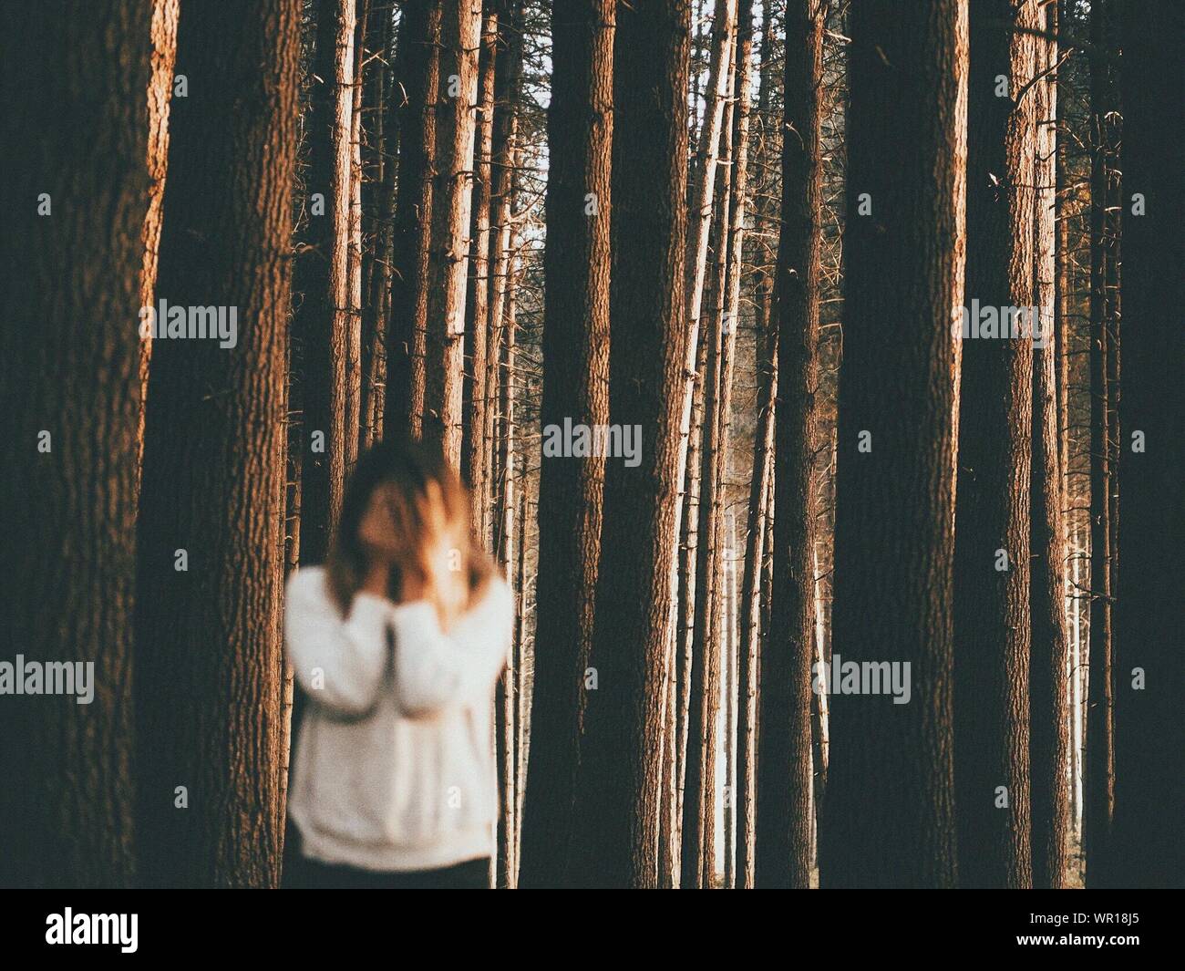 Sad Woman Standing Against Trees In Forest Stock Photo - Alamy