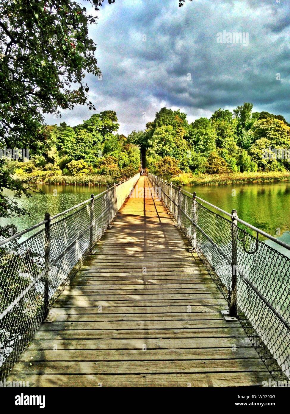 Narrow Footbridge Over Lake With Trees In Background Stock Photo - Alamy