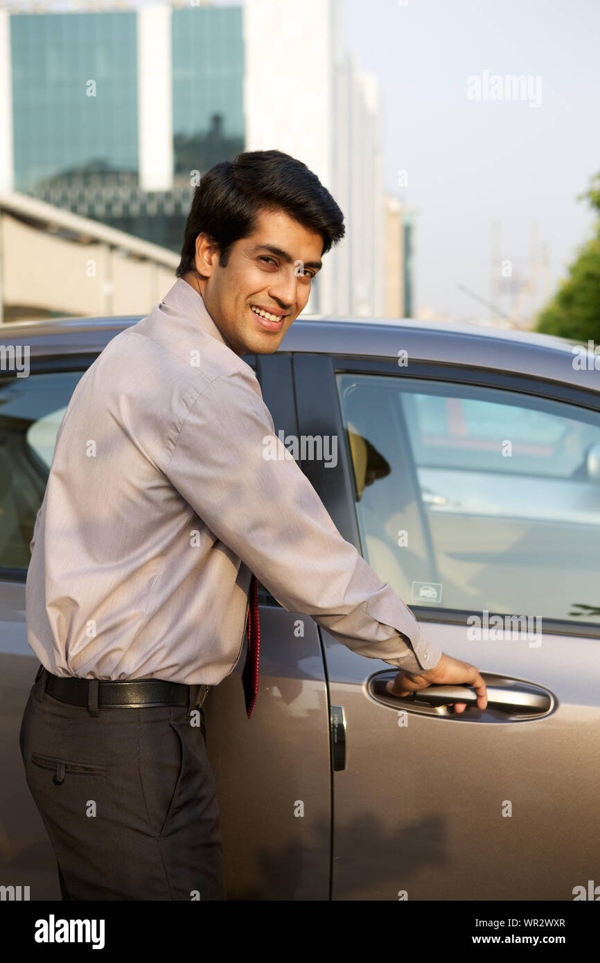 Businessman opening car door and smiling Stock Photo - Alamy