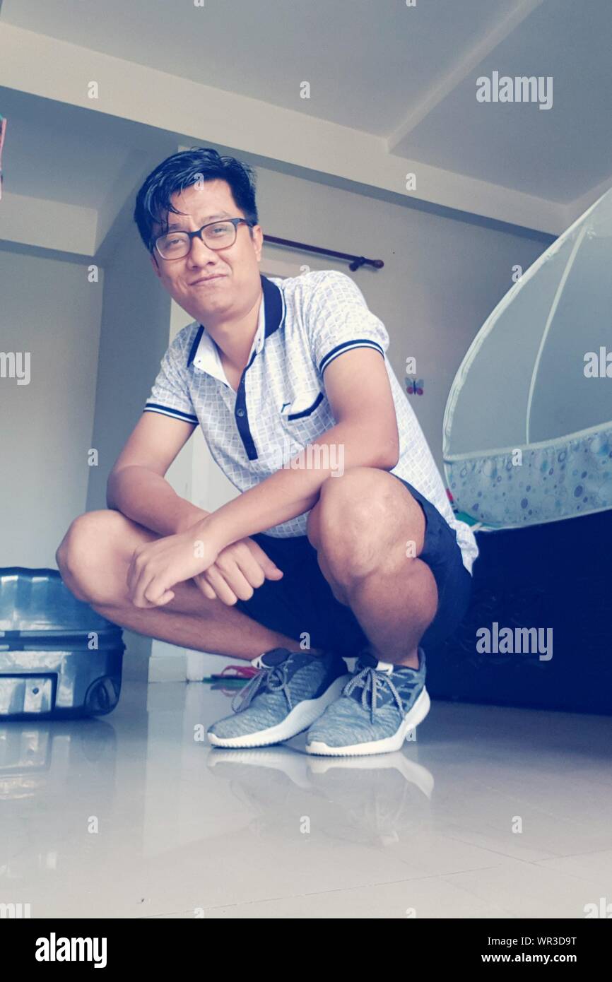 Full Length Portrait Of Man Crouching At Home Stock Photo - Alamy