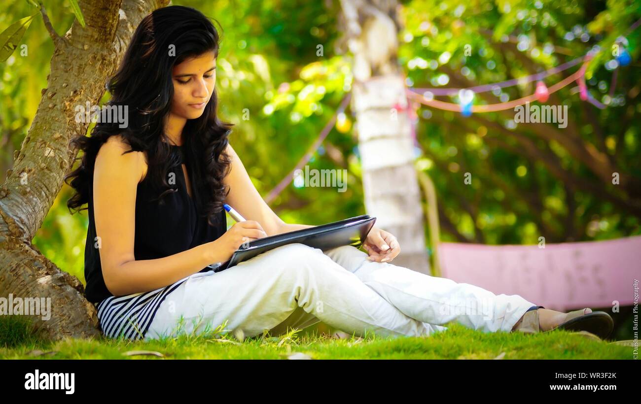 Woman sitting under tree writing hi-res stock photography and images ...