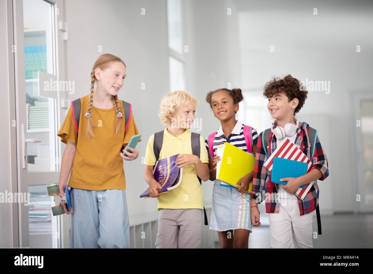 Children with backpacks and books walking to classroom Stock Photo - Alamy