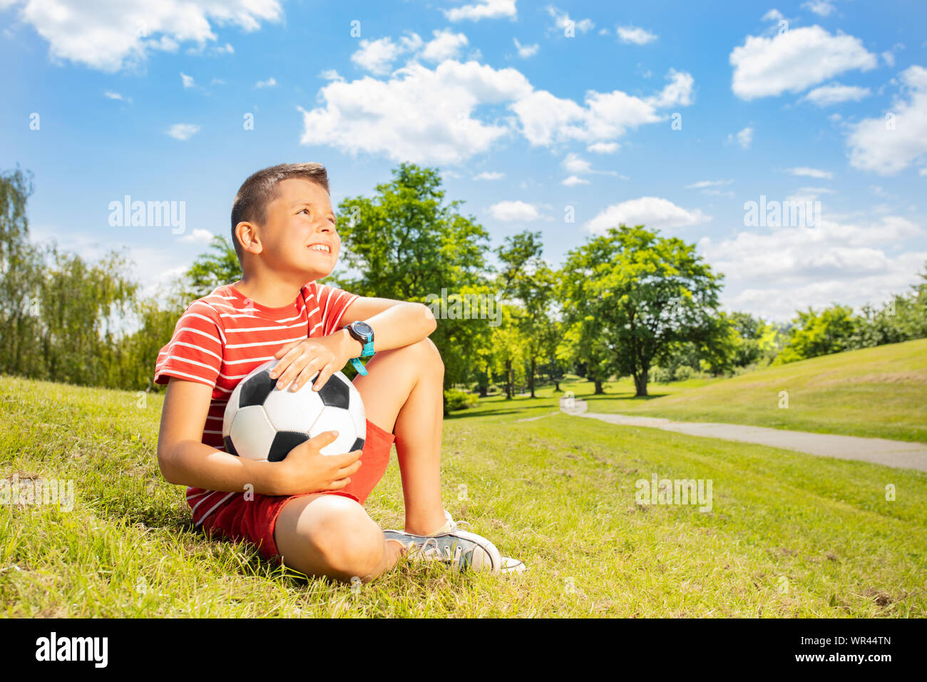 Cute Caucasian boy with football ball in park lawn Stock Photo - Alamy