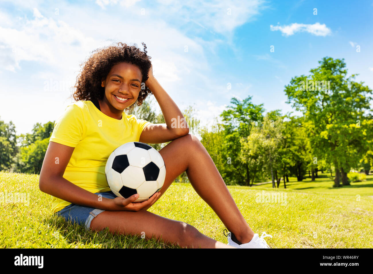 Lovely young black curly girl with football ball Stock Photo - Alamy