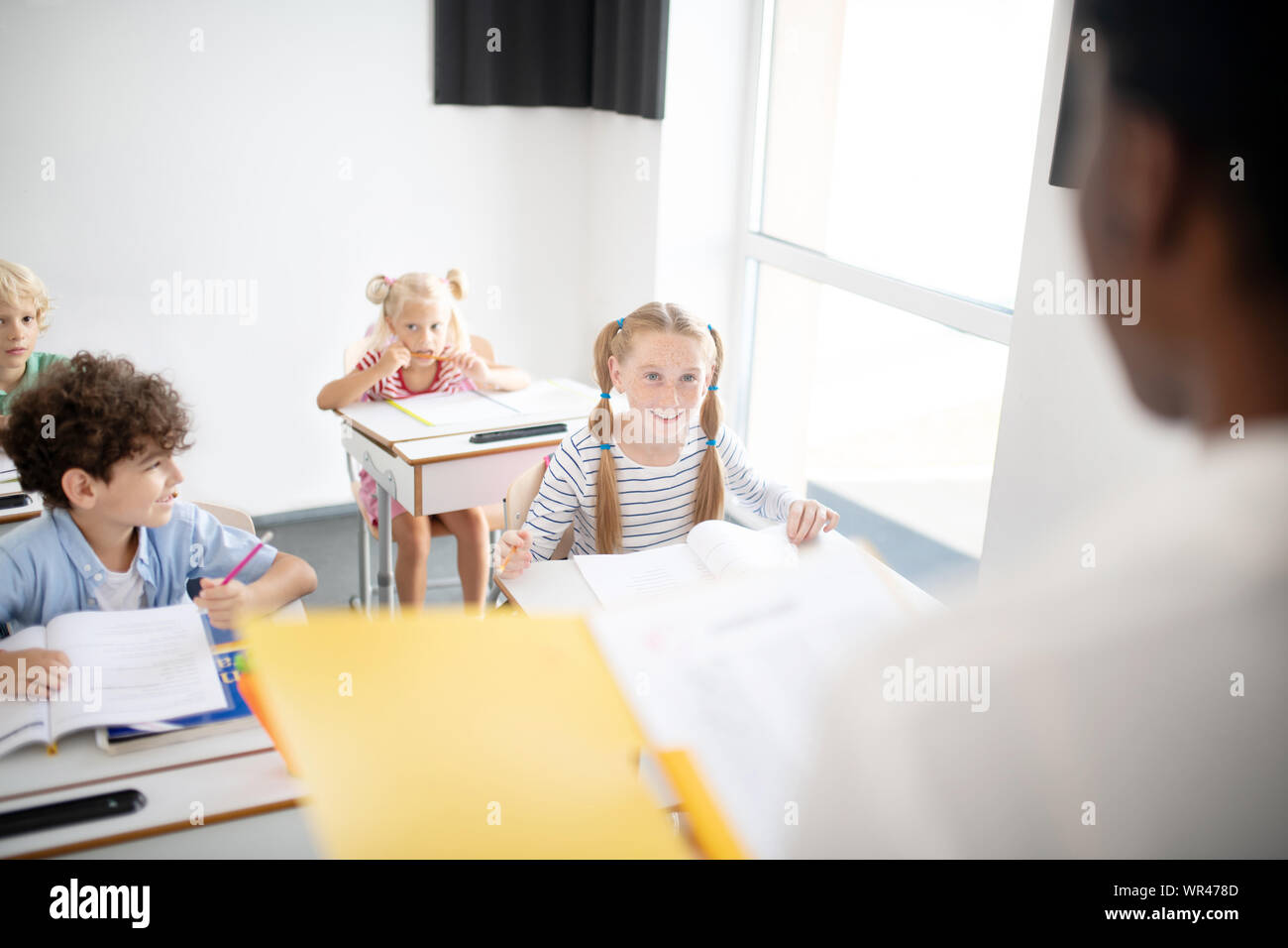 Smiling children listening to their teacher attentively Stock Photo - Alamy