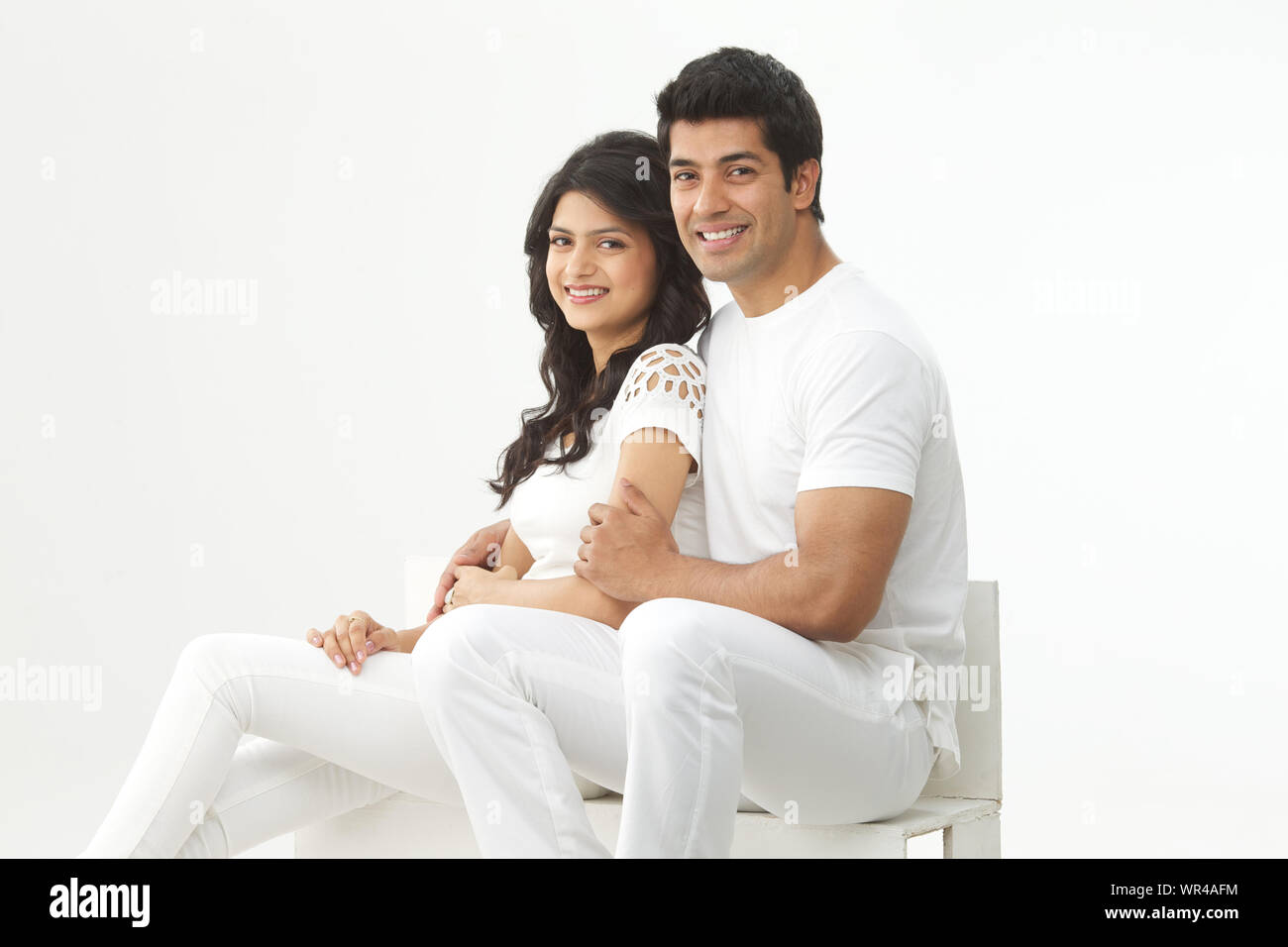 Young couple sitting together and smiling Stock Photo - Alamy