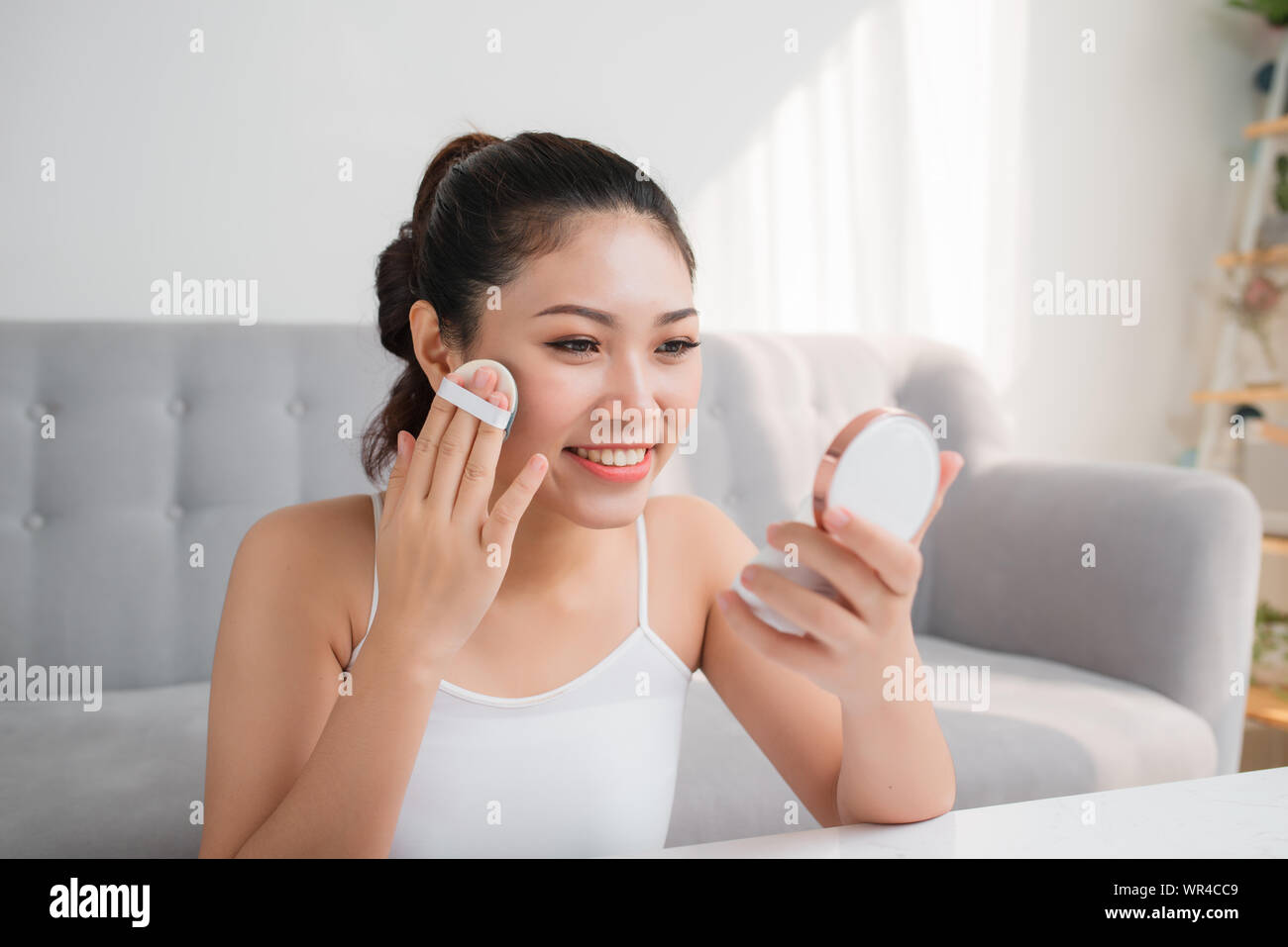 Portrait of a Beauty young woman cosmetics looking in the mirror using ...