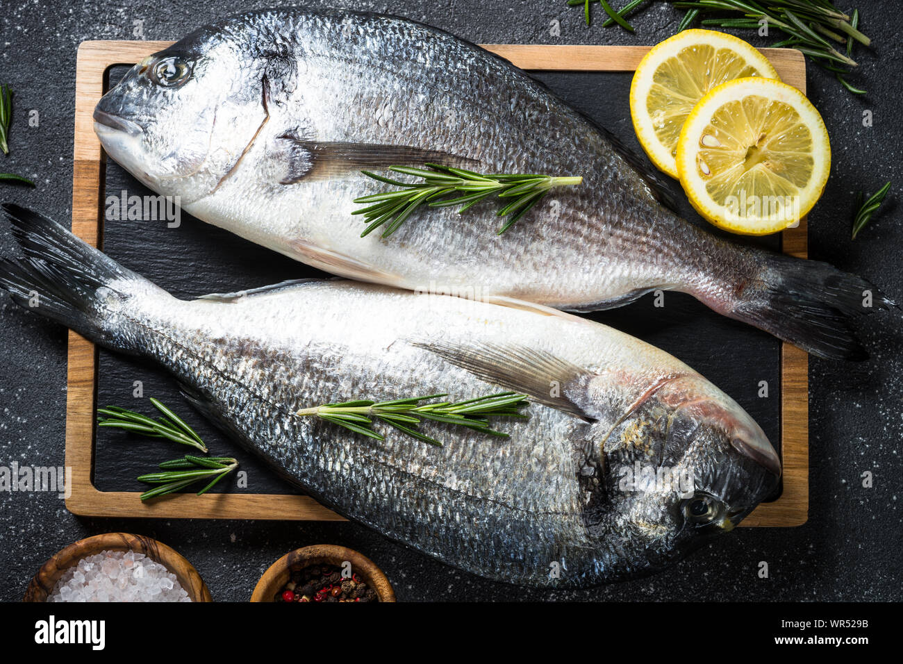 Raw dorado fish on black Stock Photo - Alamy