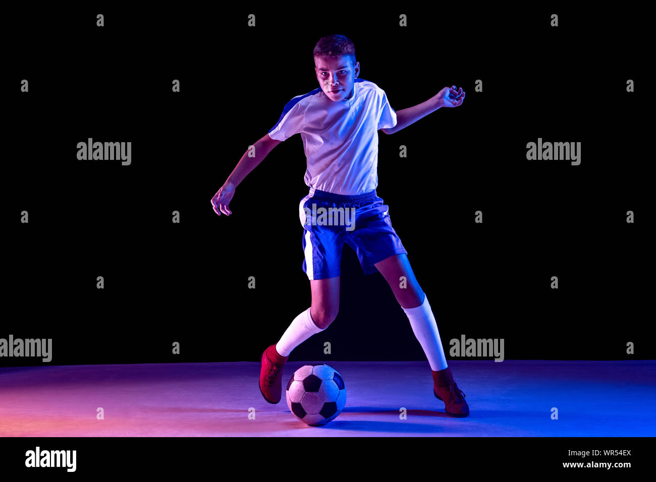 Young boy as a soccer or football player in sportwear making a feint or ...