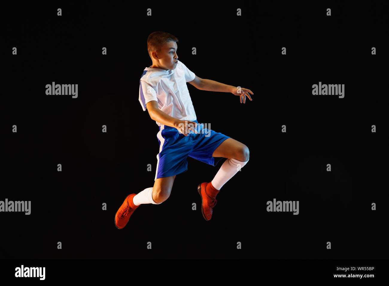 Young boy as a soccer or football player in sportwear making a feint or ...