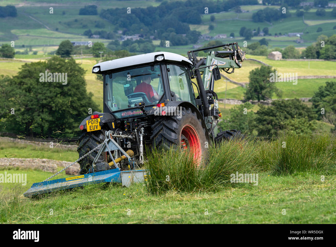 Topping overgrown grass on an upland pasture with a Hurlimann tractor ...