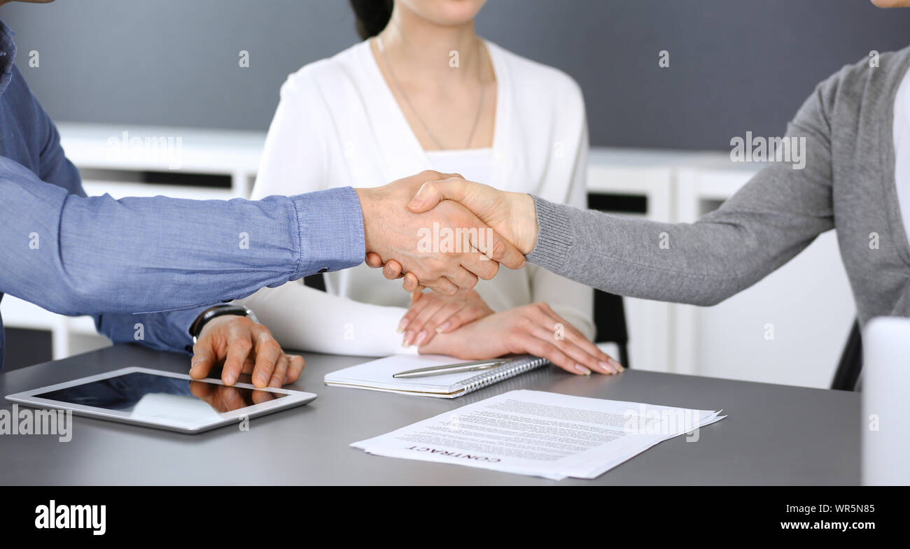 Group of business people shaking hands after discussing questions and achieving agreement at ...
