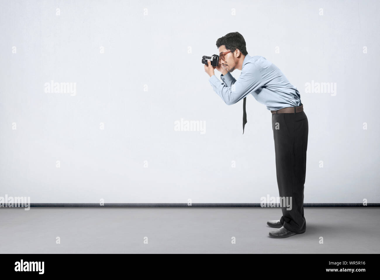 Asian businessman take a picture with his camera over white wall ...