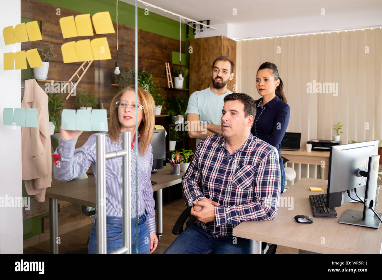Creative team plan a new project in front of a note glass in the modern ...