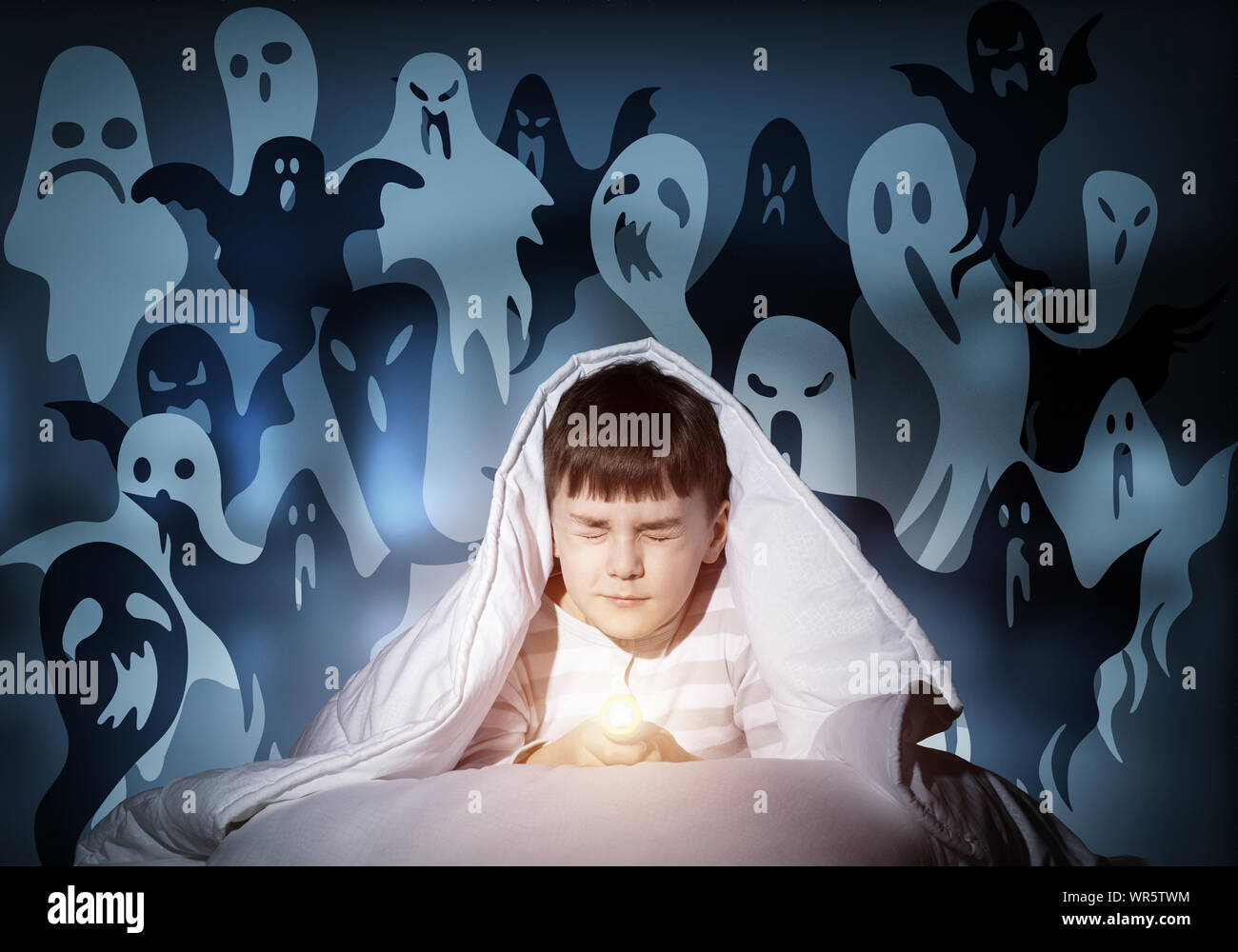 Young boy hiding under blanket from imaginary ghosts. Scared kid with ...