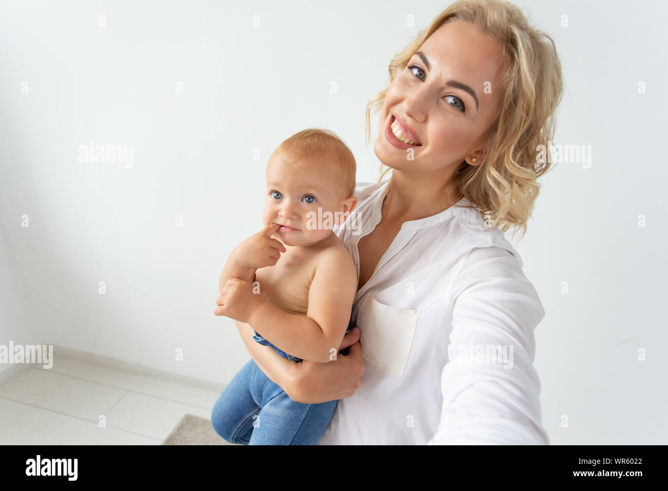 Cute little baby girl and her mother taking selfie in a living room ...