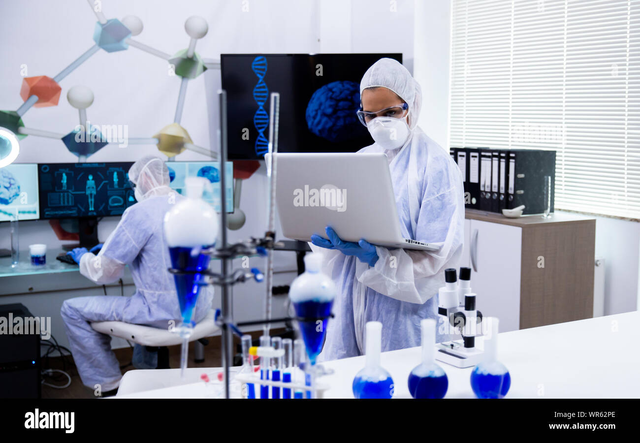 Scientist in modern research laboratory standing and working on laptop ...