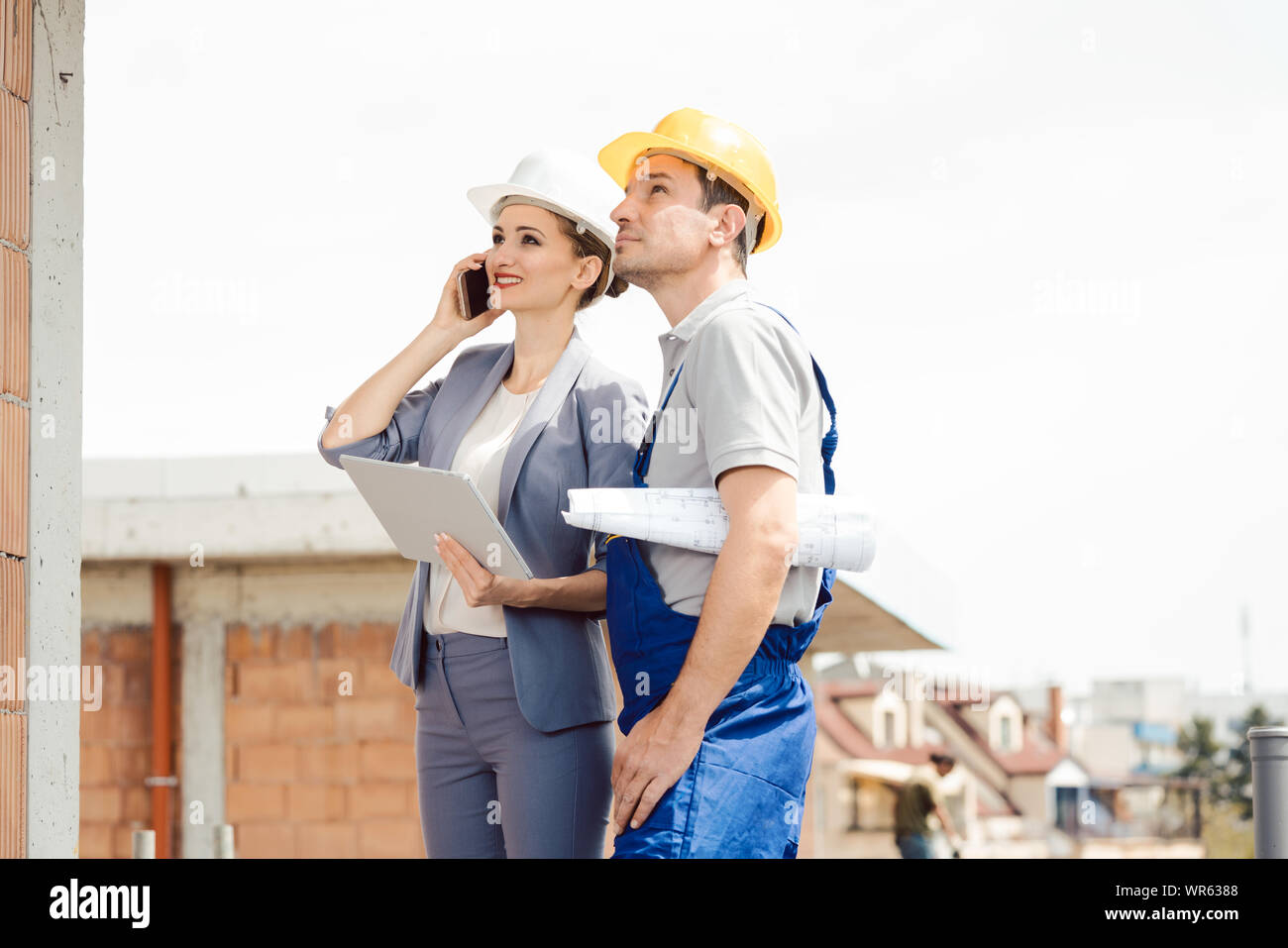 Project developer and construction worker on site using technology ...