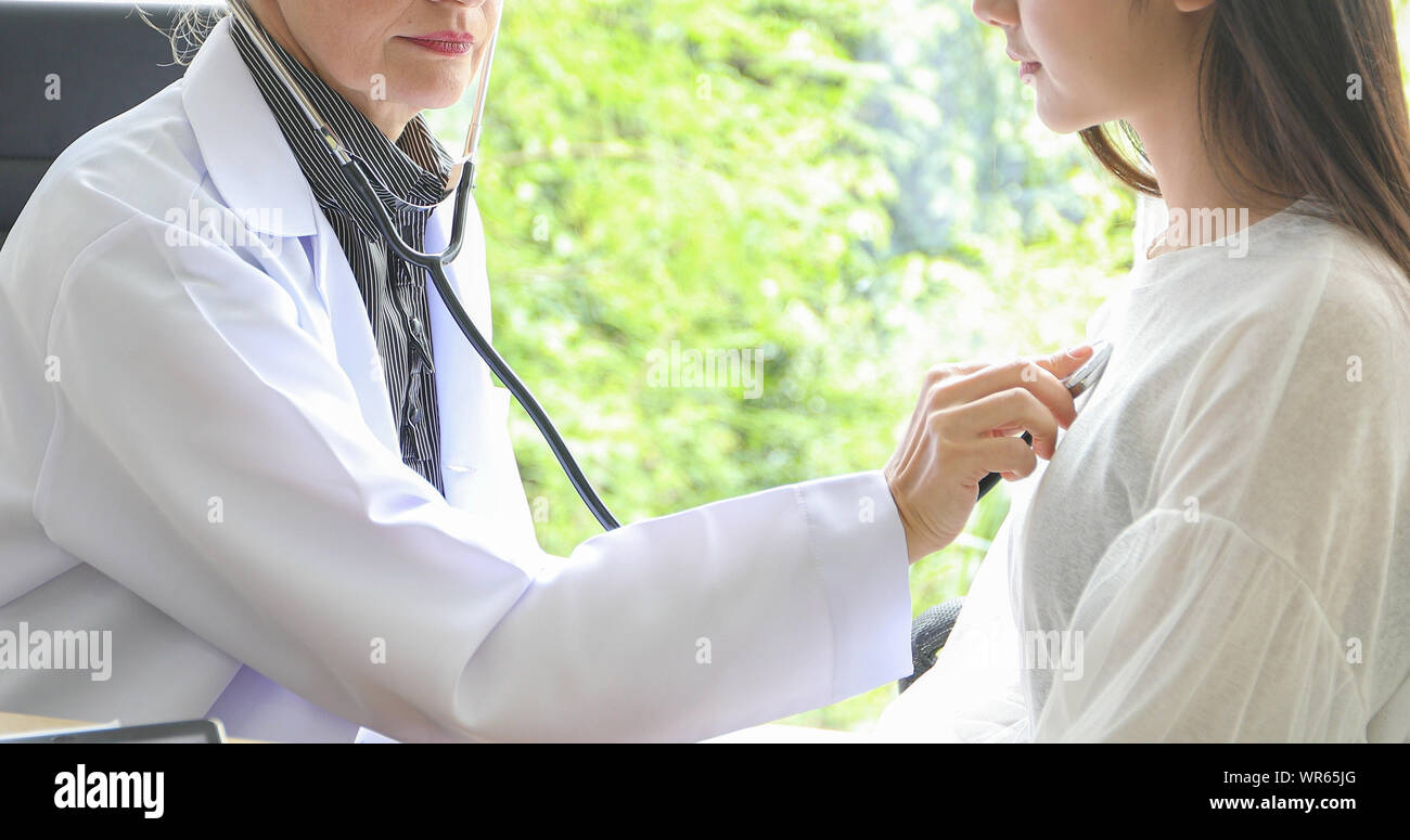 Doctor using stethoscope for examining patient in his office at ...