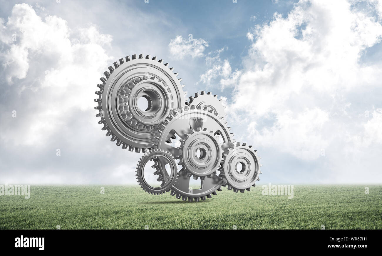 Abstract mechanism with cogwheels on green meadow. Construction and ...