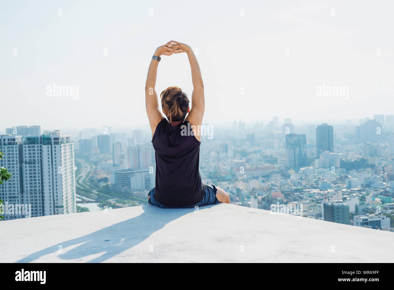 Man sitting on black roof and show hand up with blue sky background and ...
