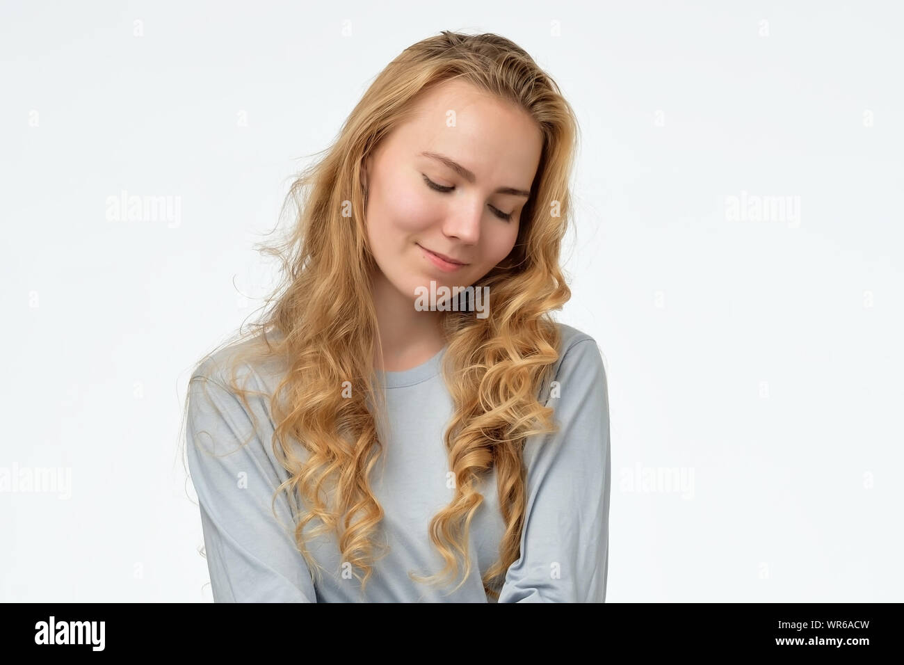 Timid young caucasian female looking down with shy smile, being ...