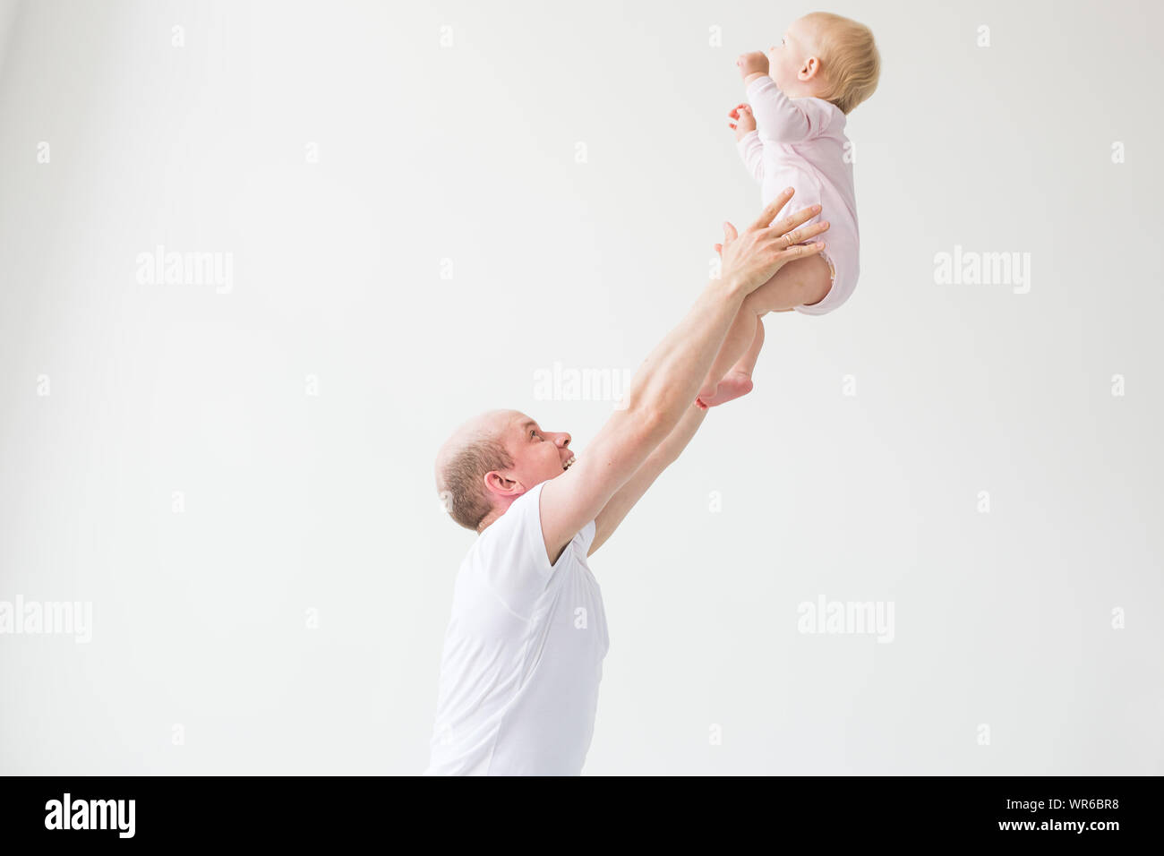Happy young father lifting cute baby up high in air, spending and ...