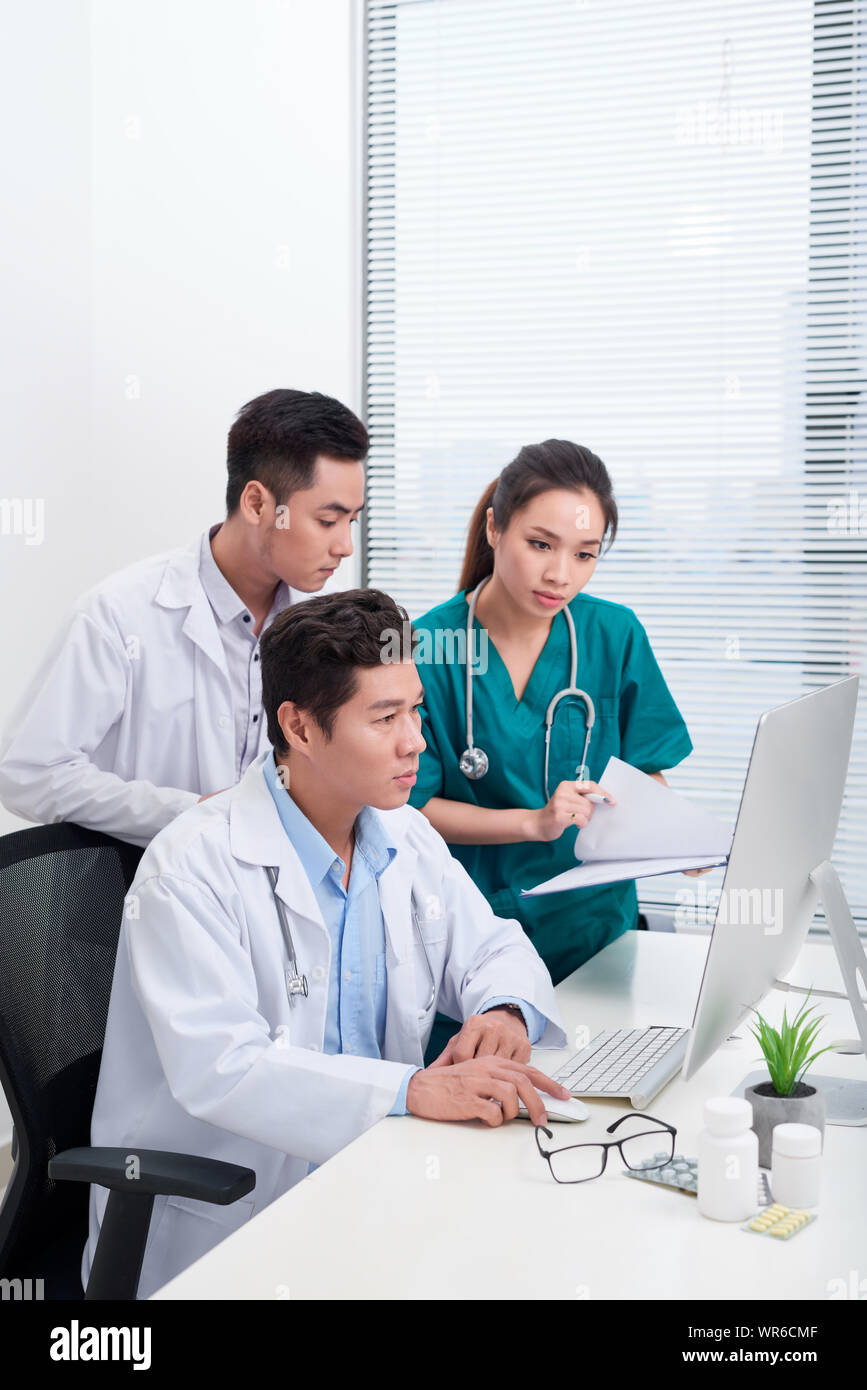 Two male doctors and female surgeon discussing at the hospital office ...