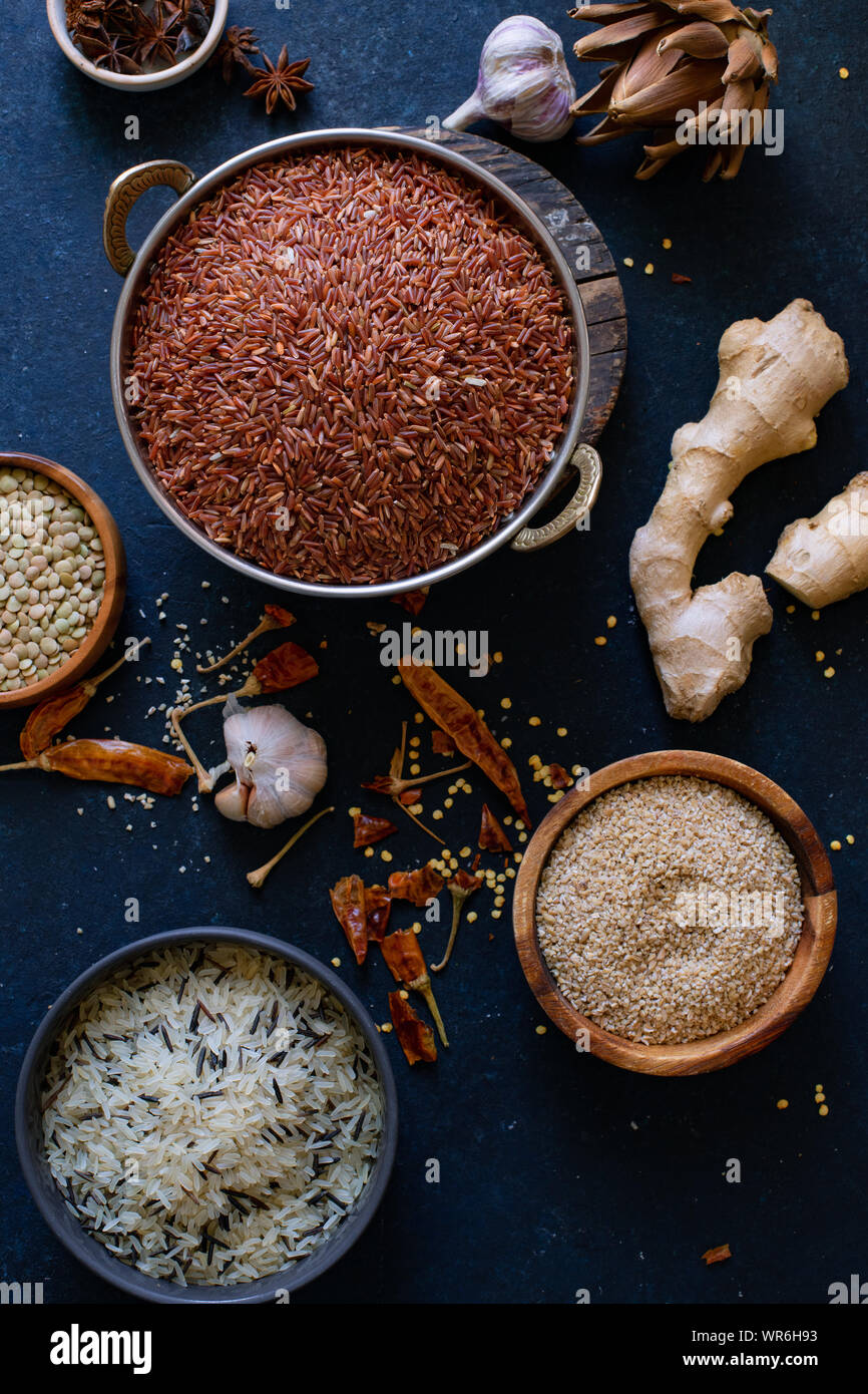 Various types of rice and grains with spices on blue background. Brown ...