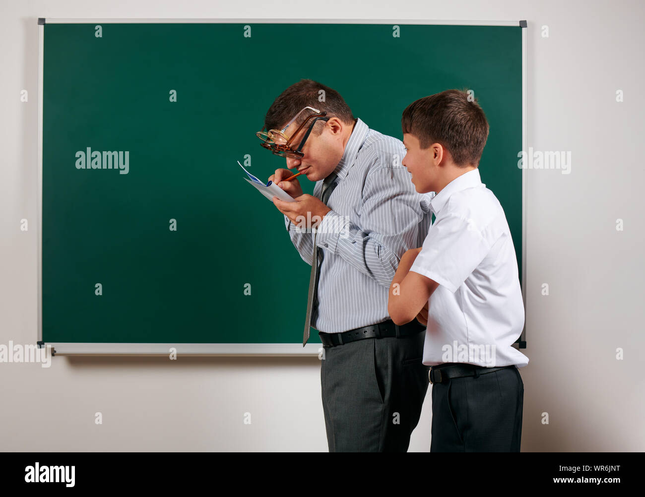 Portrait of a teacher checking homework, reading school exercise books ...