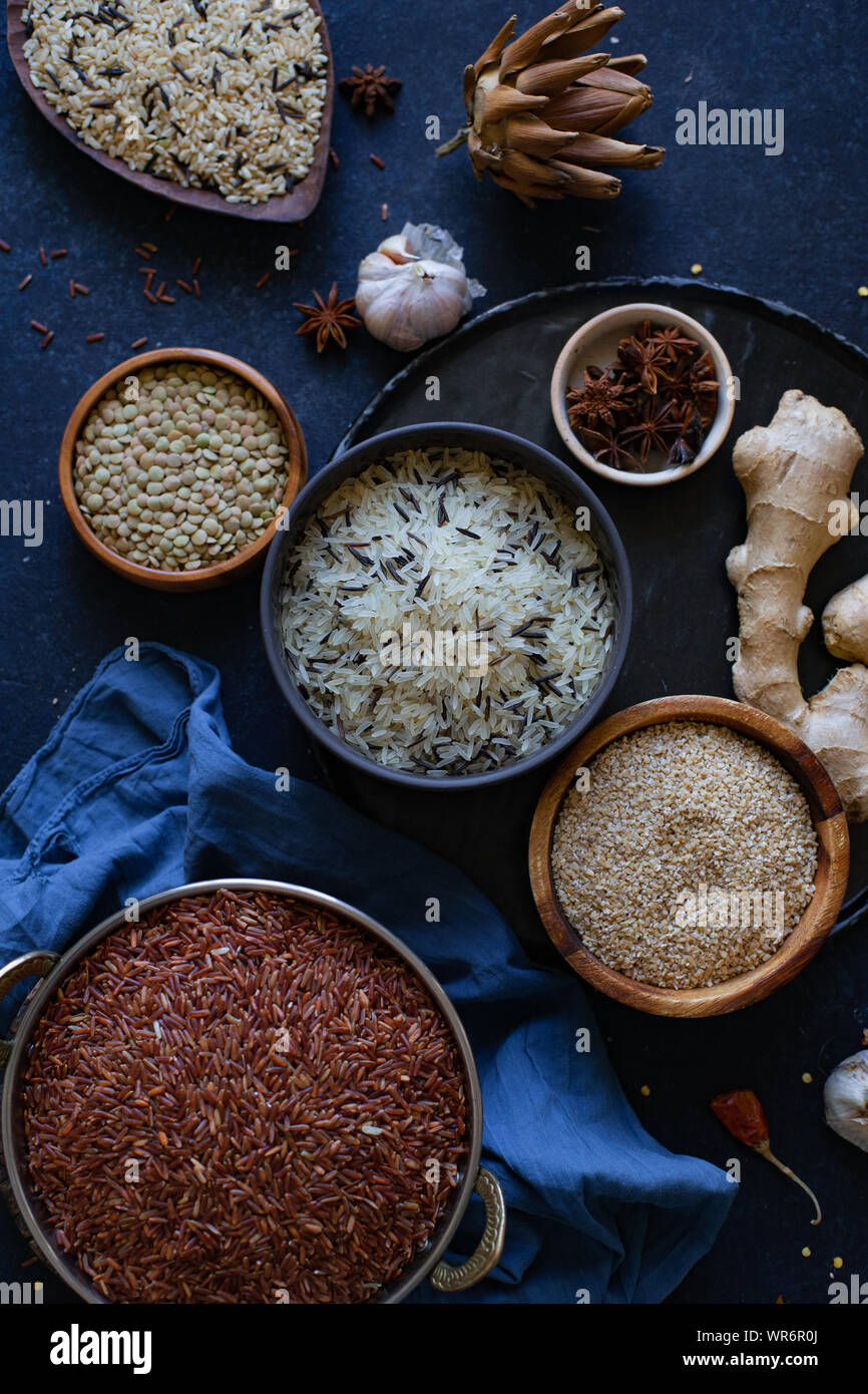 Various types of rice and grains with spices on blue background. Brown rice and mixed wild rice ...