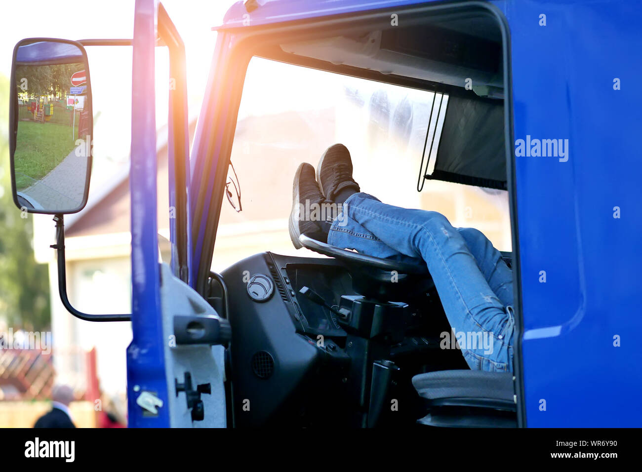 the truck driver rests in the cab of the car with his feet on the ...