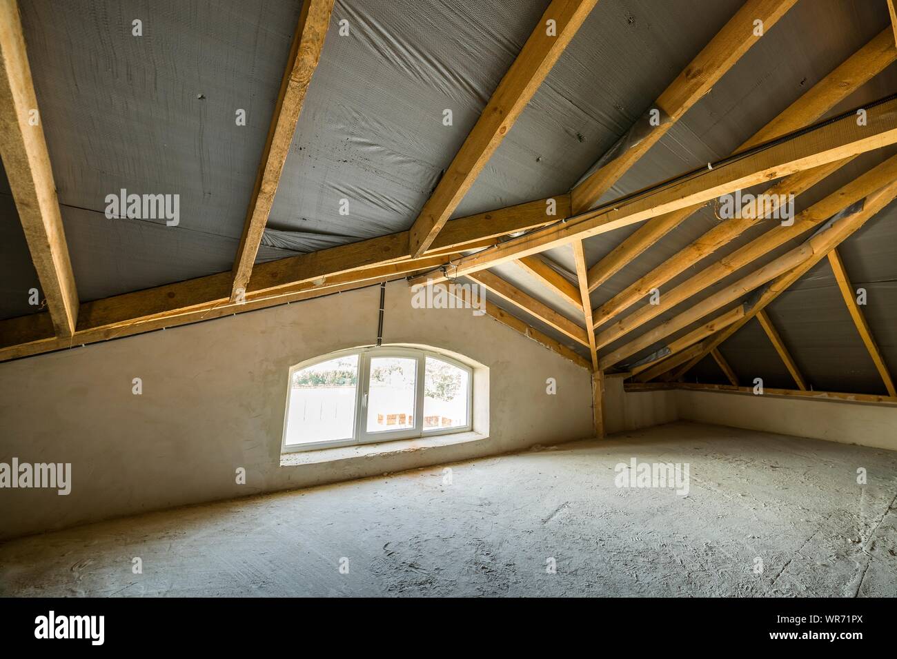 Attic of a building with wooden beams of a roof structure and a small ...