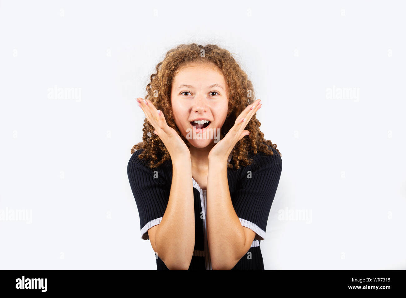Young girl positively surprised with hands on her cheek. Beautiful ...