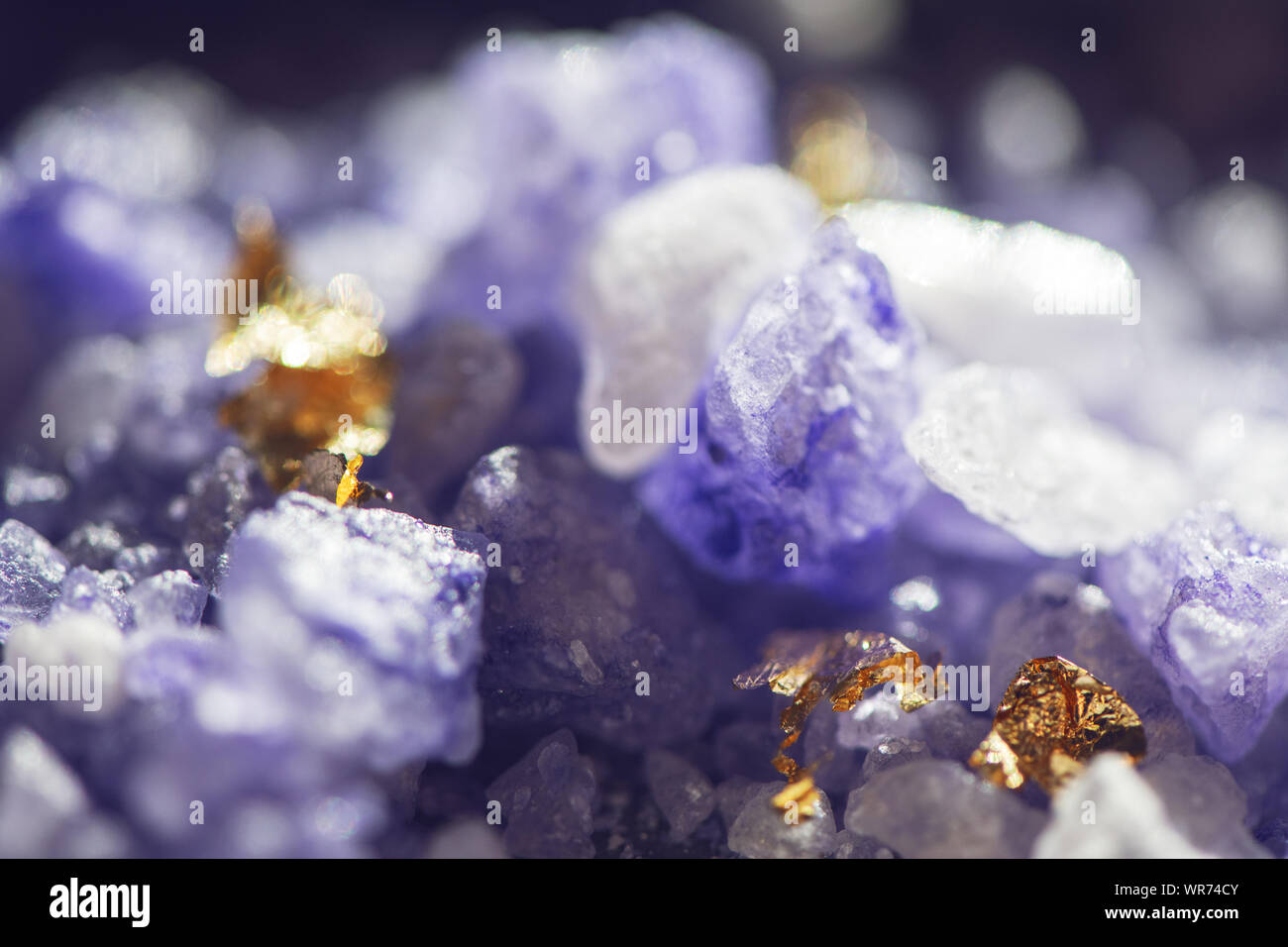 Violet crystals of natural sea salt with gold foil close-up background ...