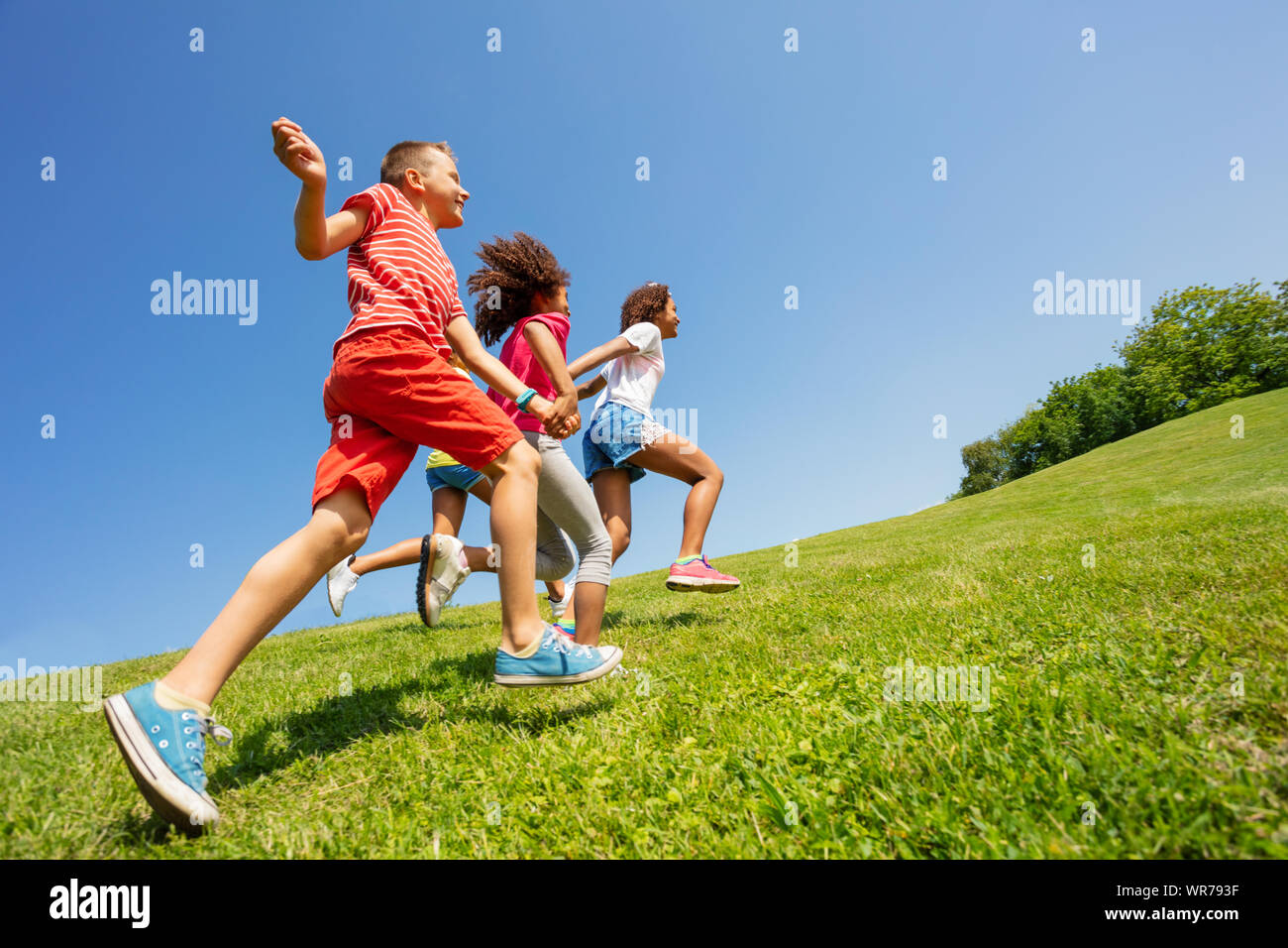 Profile view of cute kids run in park hold hands Stock Photo - Alamy