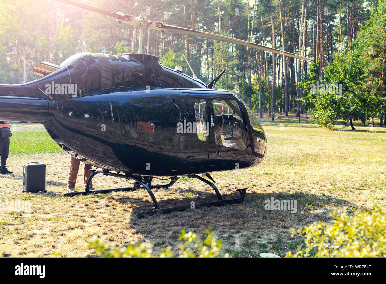 Black private modern luxury helicopter standing on grass field near ...