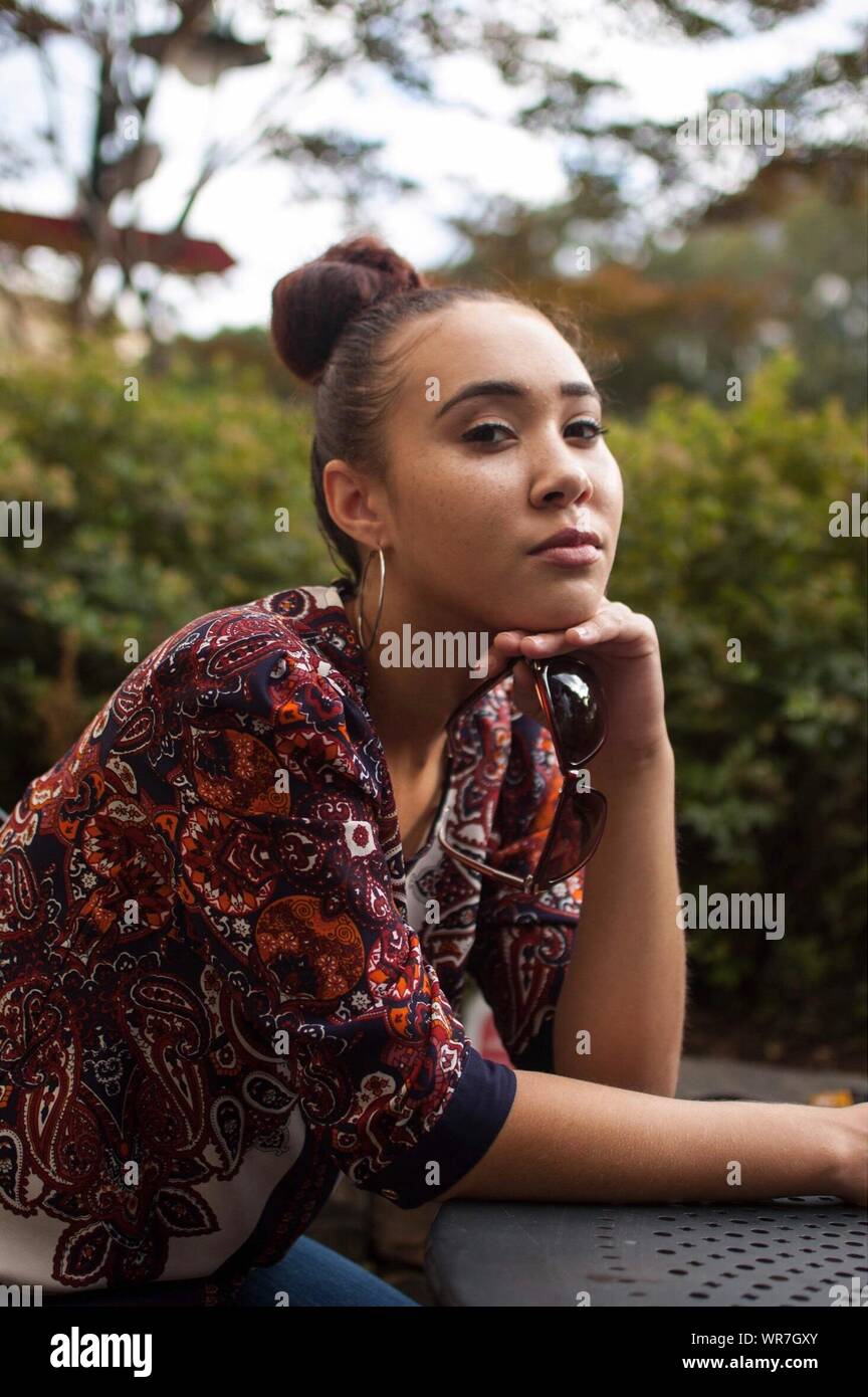 Young Woman Sitting Against Tree Stock Photo - Alamy