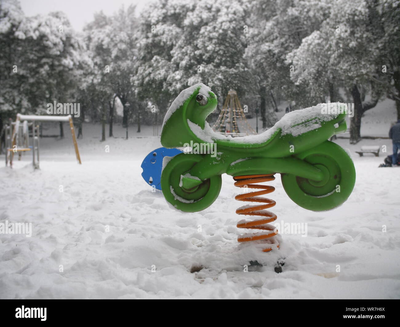 Spring ride covered in snow in deserted kids playground. Shape of fish ...
