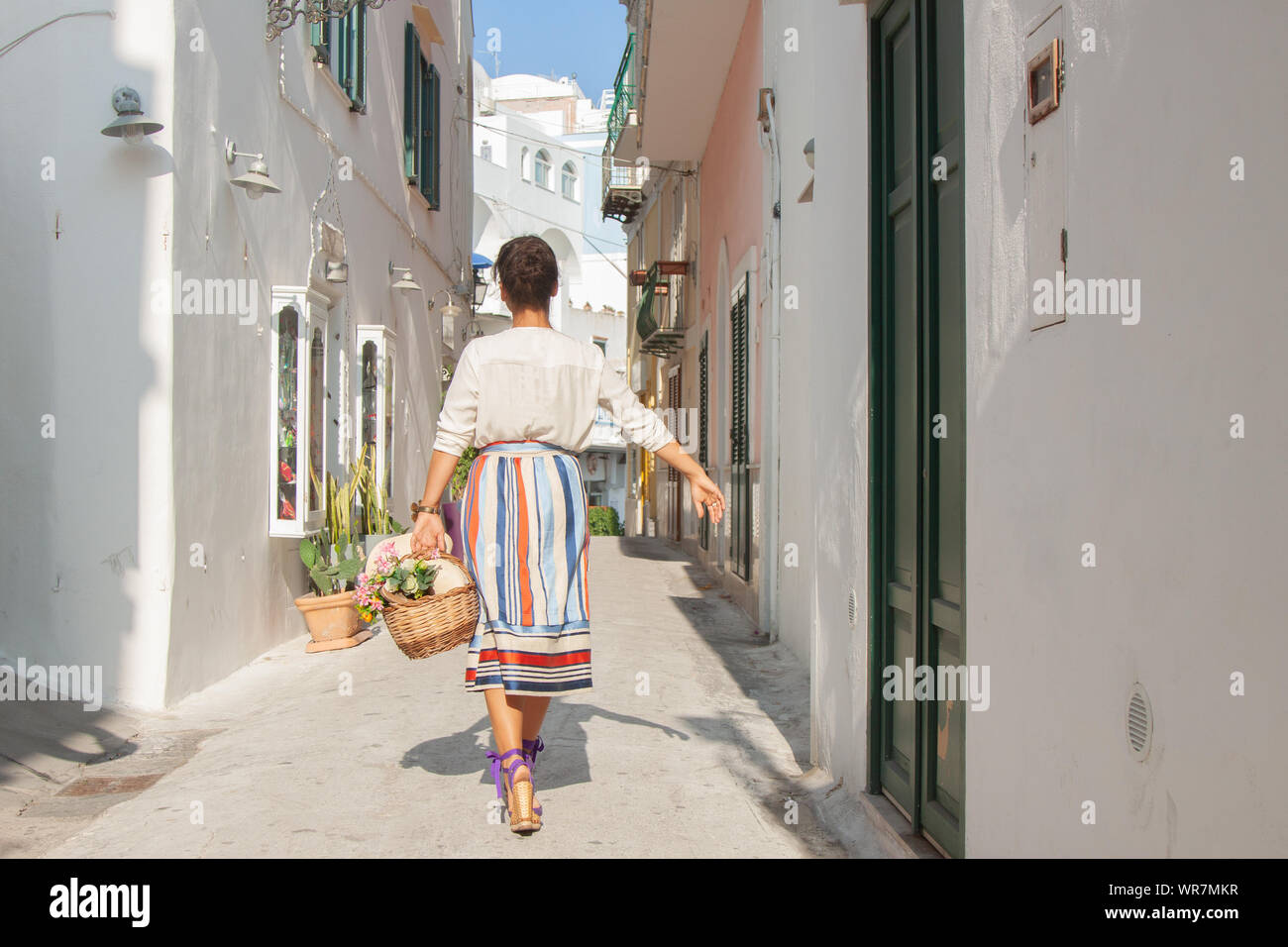 Young woman walking in a typical alley on Ponza island town, Italy ...