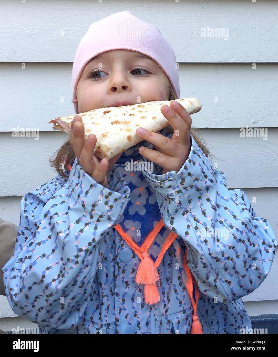 Cute Girl Eating Food Against Wall Stock Photo - Alamy