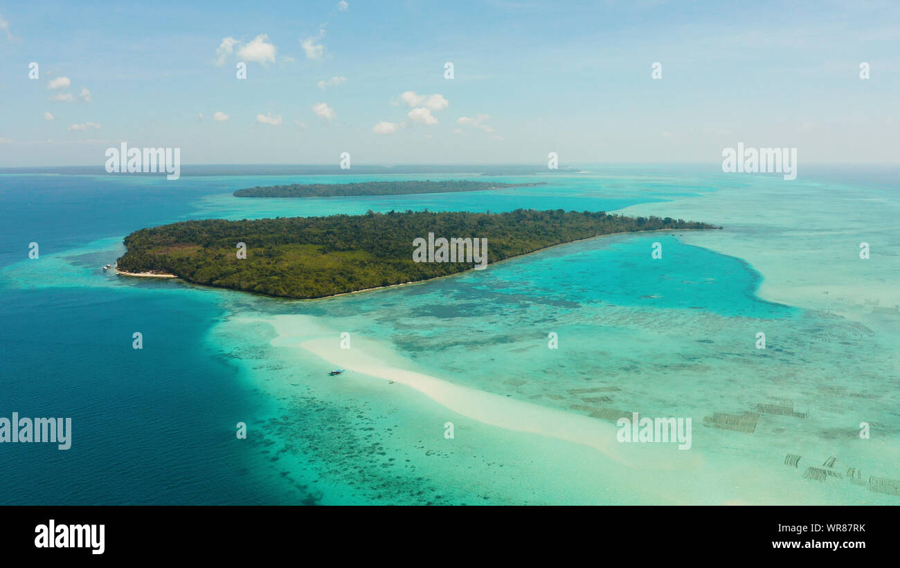 Island with a sandy beach and azure water surrounded by a coral reef ...