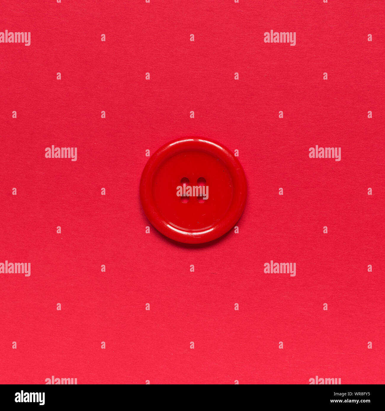 Single red sewing button on red background Stock Photo - Alamy