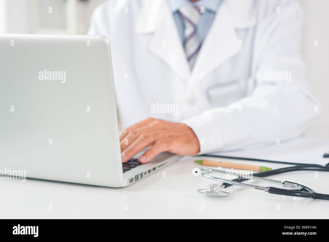 Senior doctor at his office in hospital working close-up using laptop ...
