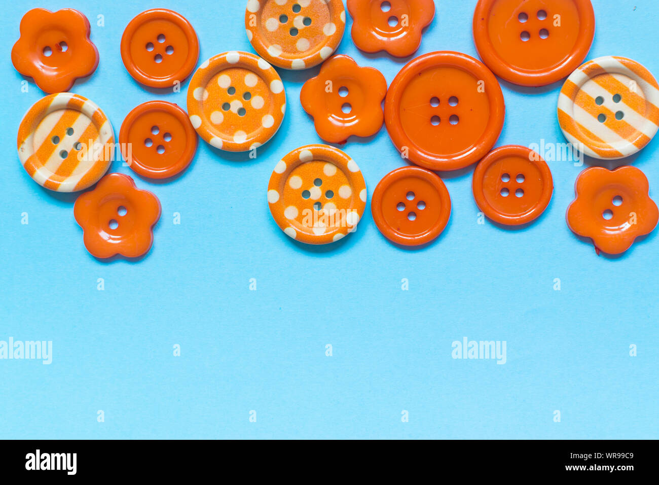 Various orange sewing buttons on blue background Stock Photo - Alamy