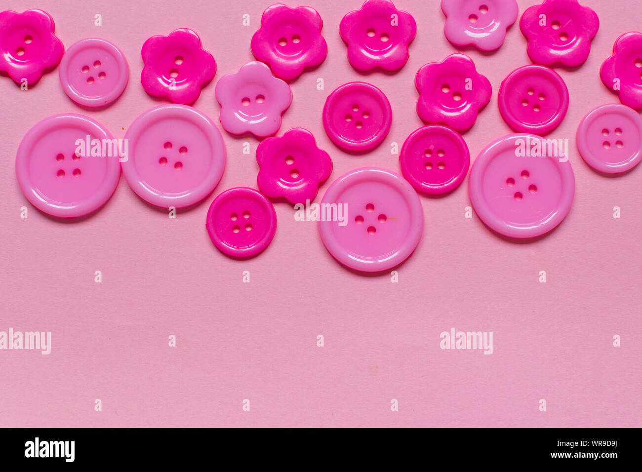 Various pink sewing buttons on light pink background with place for ...