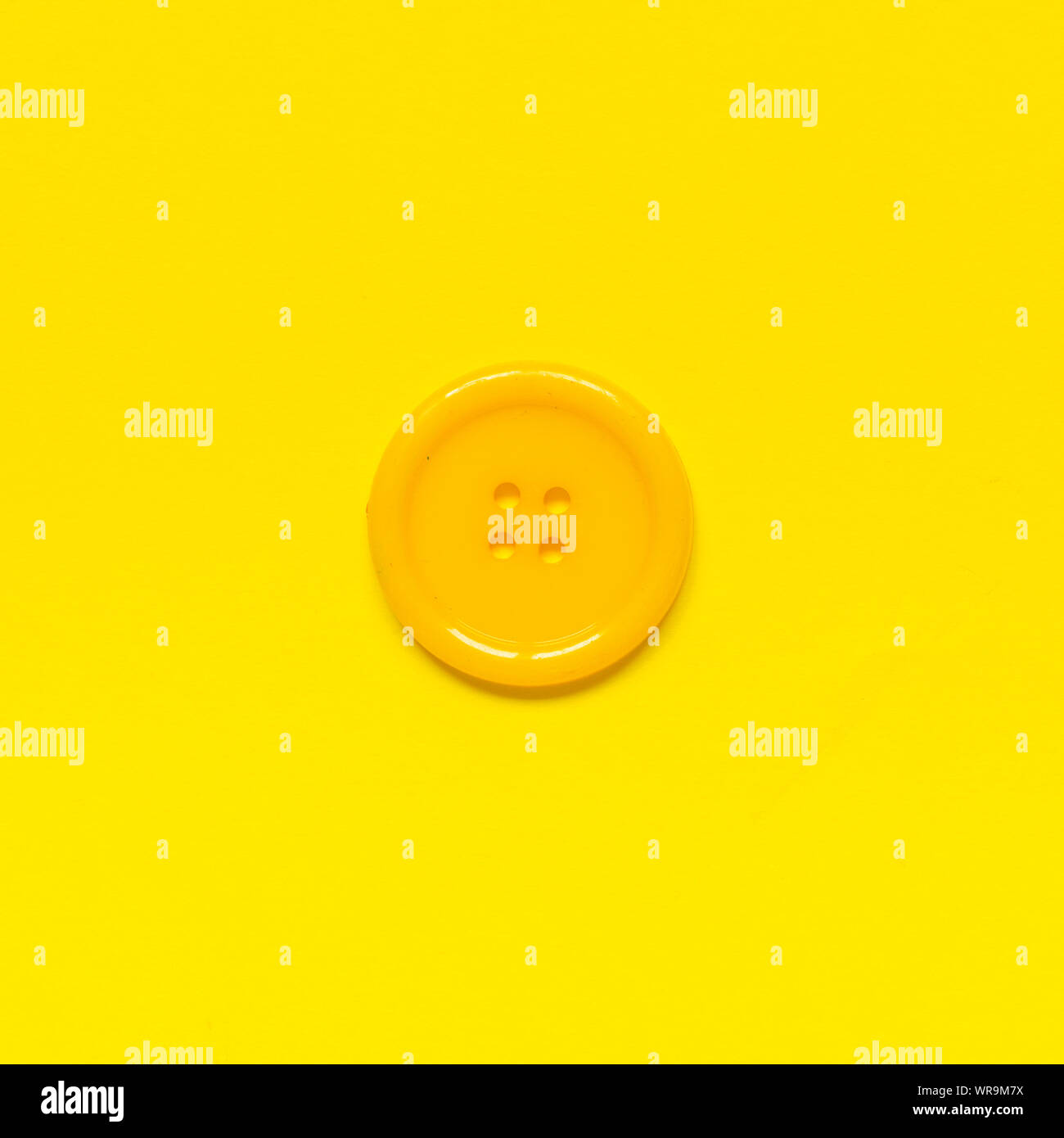 Single yellow sewing button on yellow background Stock Photo - Alamy
